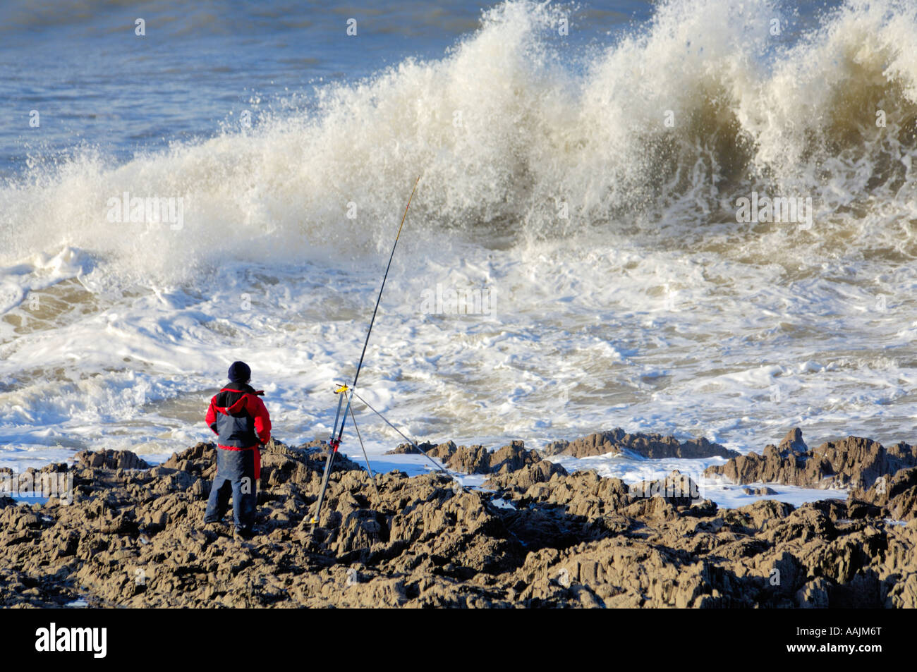 Man fishing on the North Devon coast at Westward Ho! in stormy seas ...