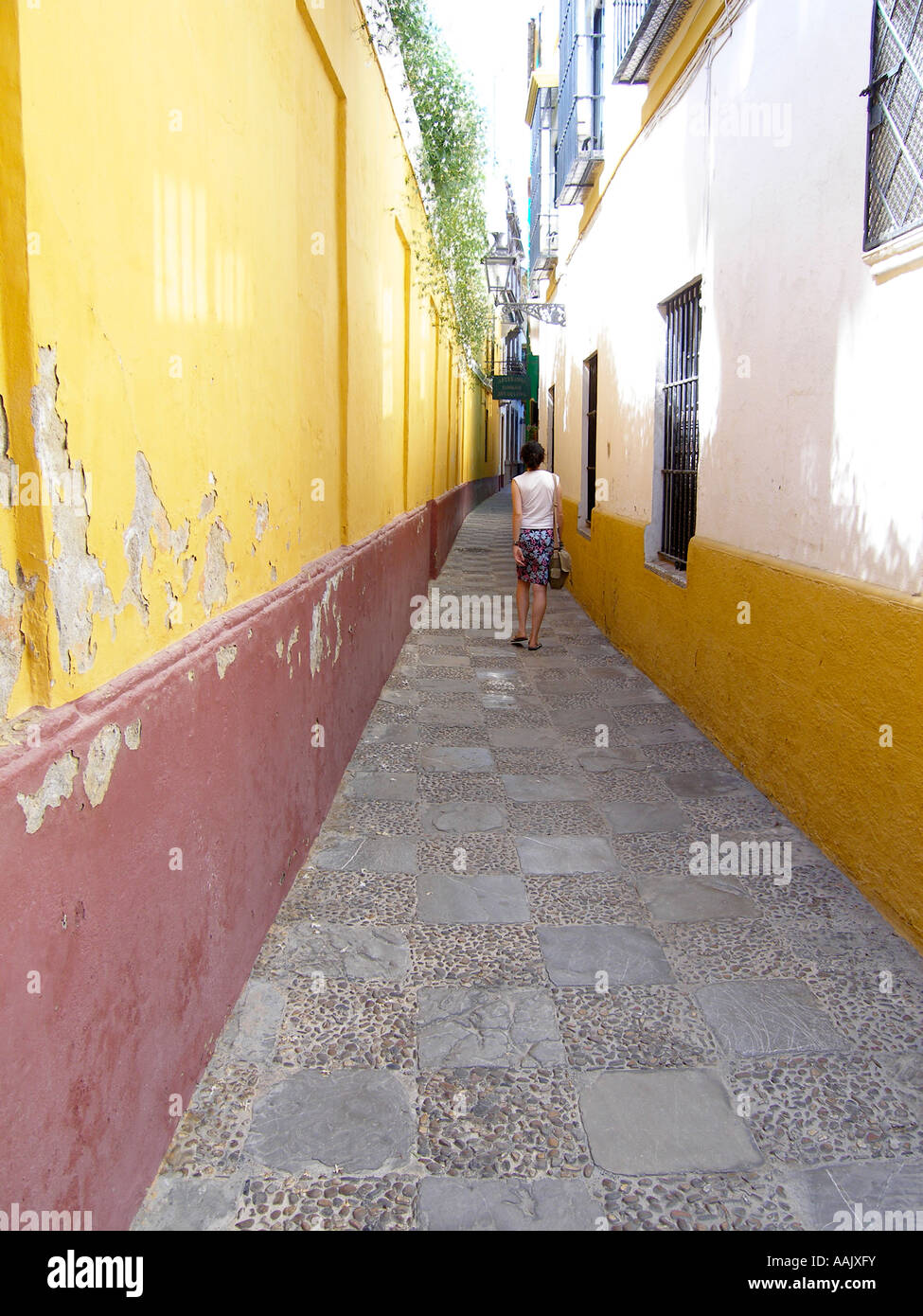 A Single Girl walking down a long narrow colorful street in Seville ...