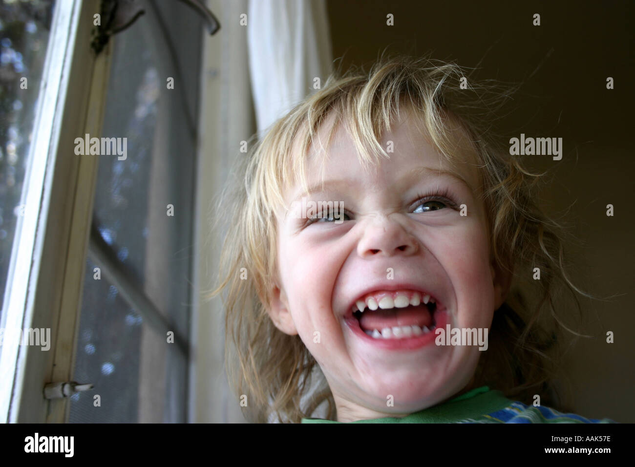 boy laughing next to window Stock Photo - Alamy