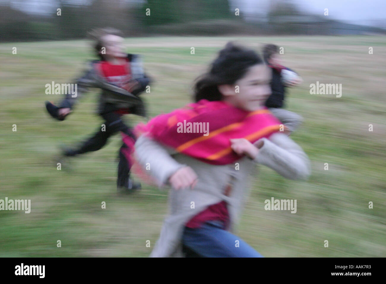 Three children running through a field on a winter’s day Stock Photo ...