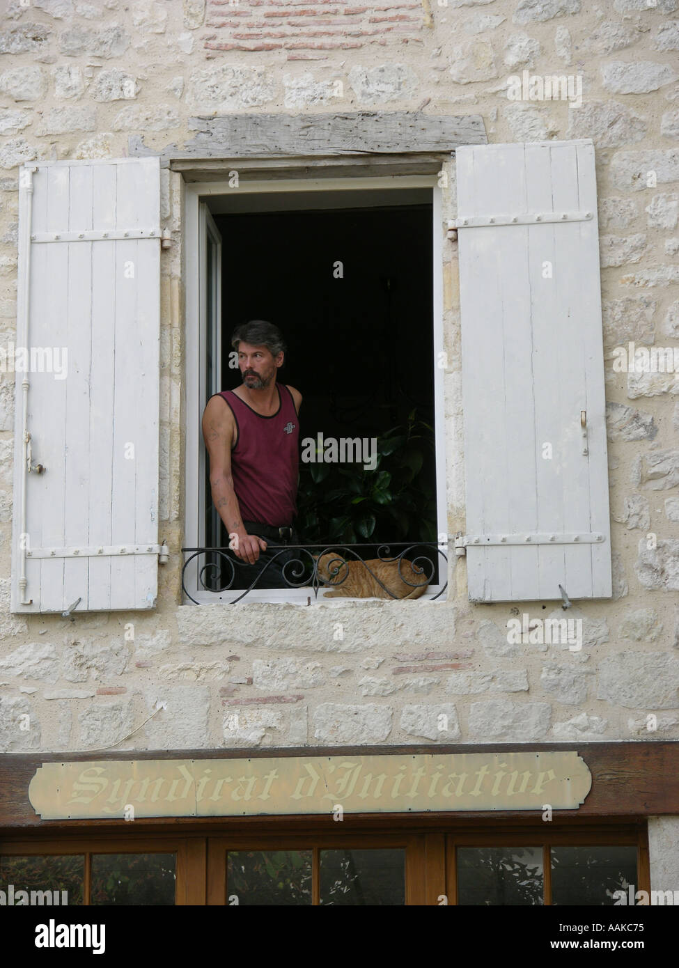 Man at window with cat looking over village square in France Stock ...