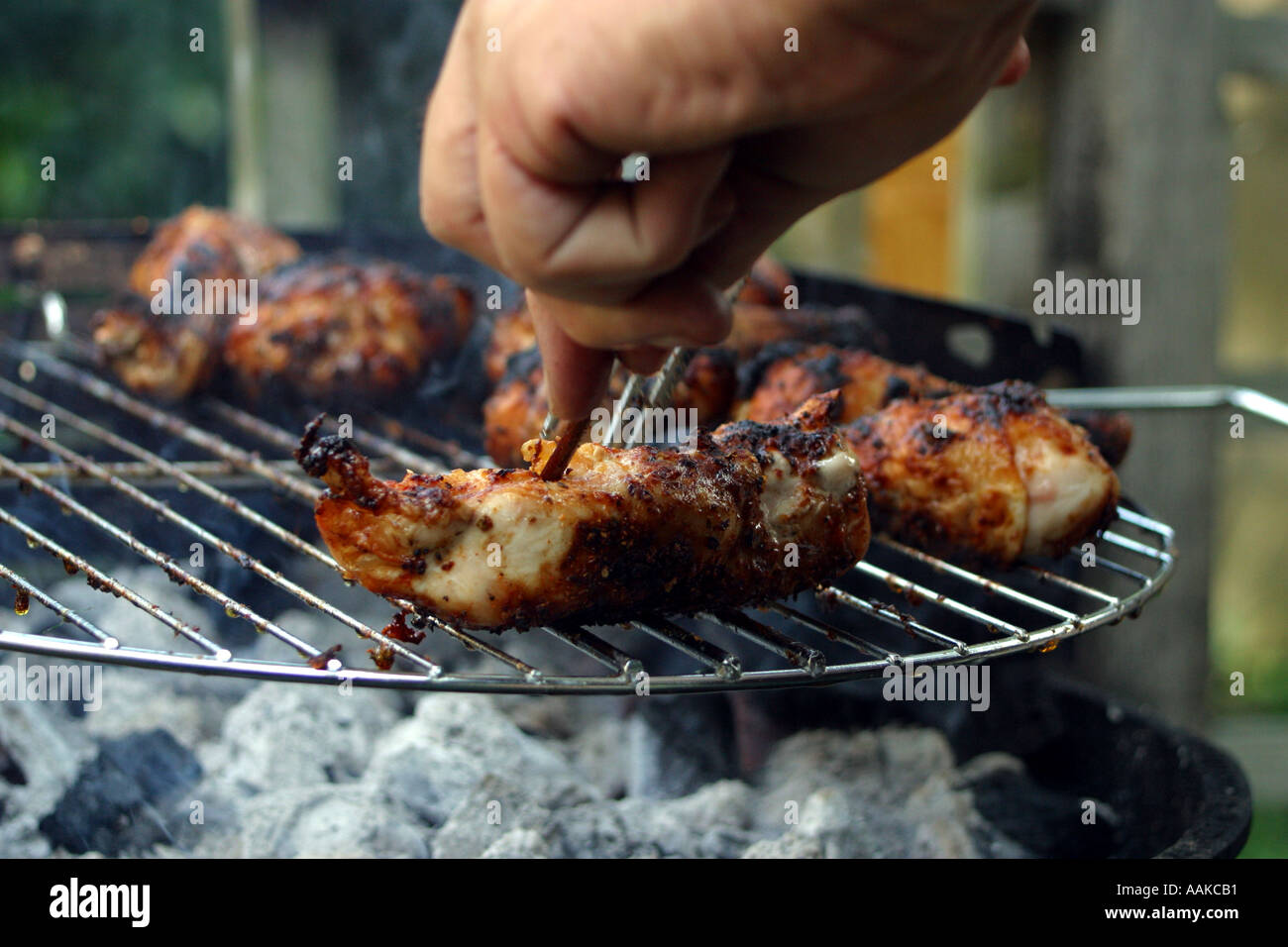 Chicken being barbecued outside over a charcoal fire Stock Photo - Alamy
