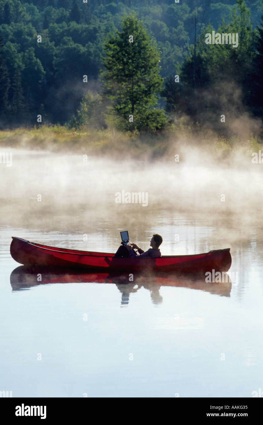 Man in canoe using laptop computer Stock Photo - Alamy
