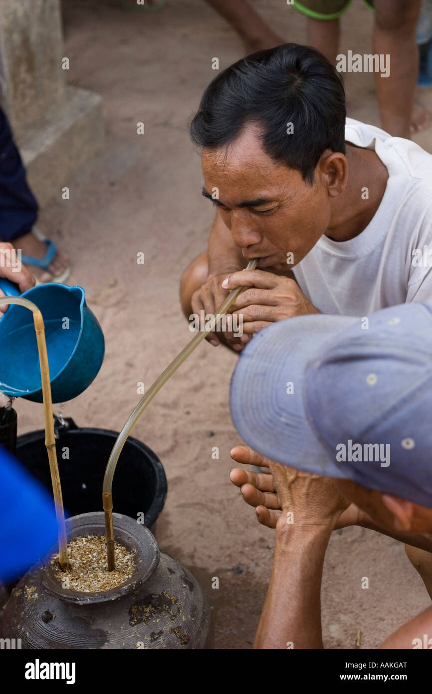 Men drinking rice alcohol through straws out of a clay pot celebrating ...
