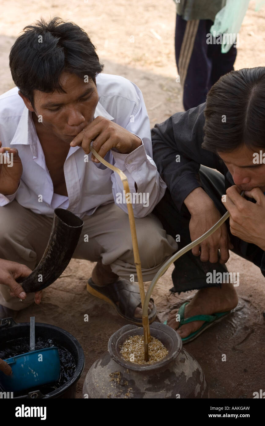Men drinking rice alcohol through straws out of a clay pot celebrating ...