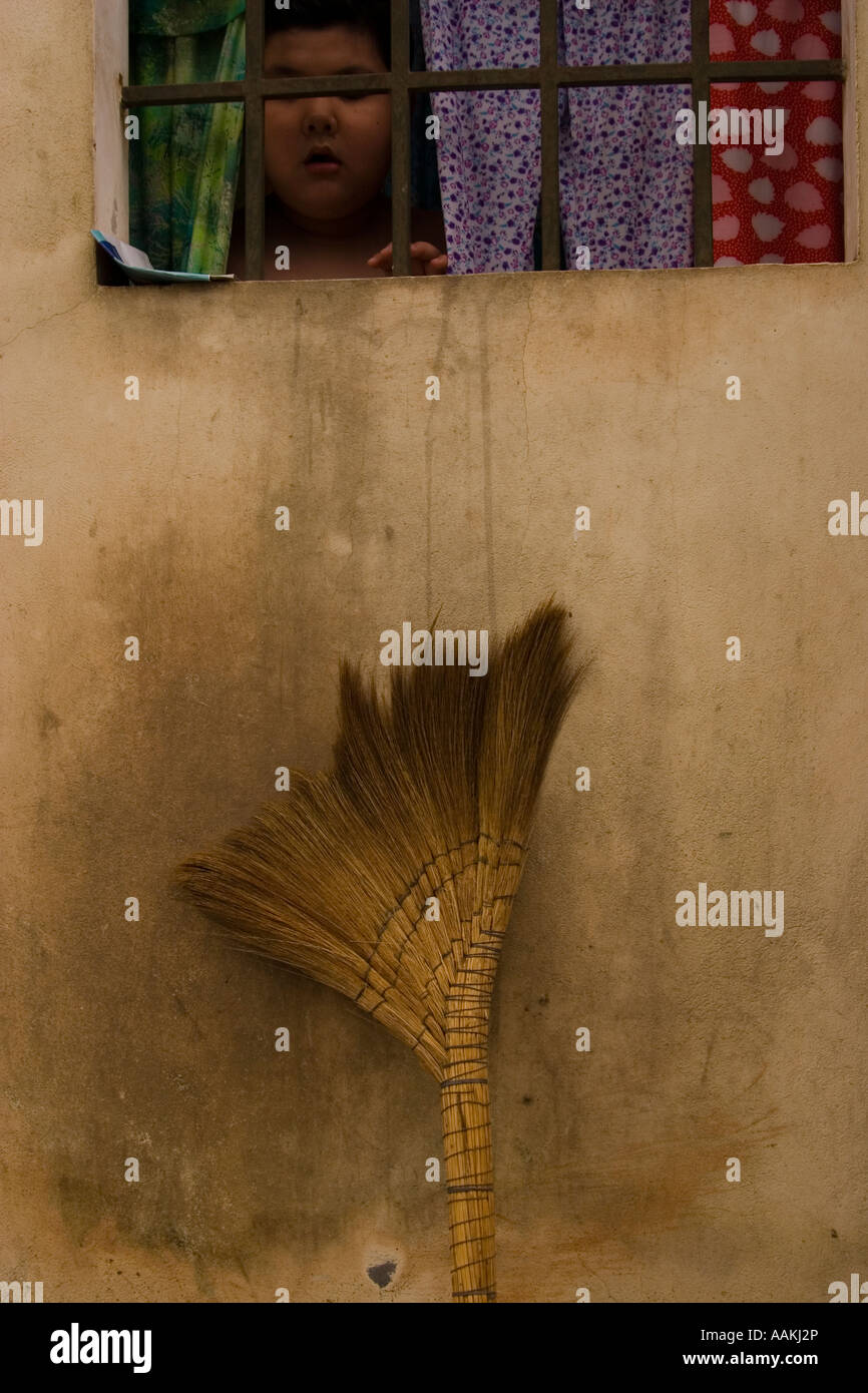 Boy peers through window with broom below Ben Tre Vietnam Stock Photo - Alamy