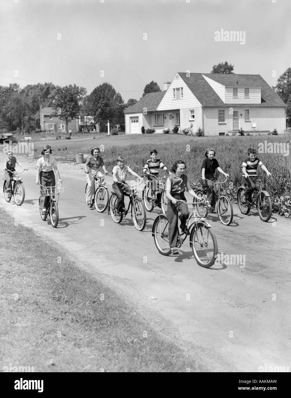 1950s GROUP OF 8 KIDS BOYS & GIRLS RIDE BICYCLES ON COUNTRY RURAL ROAD ...