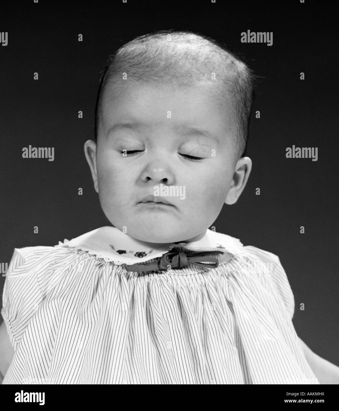 1960s PORTRAIT BABY IN STRIPED DRESS WITH EYES CLOSED & SLIGHT FROWN ...