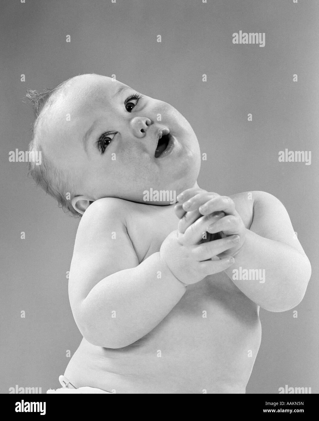 1950s BABY IN DIAPER HEAD TO ONE SIDE ARMS HANDS CLASPED IN FRONT Stock ...