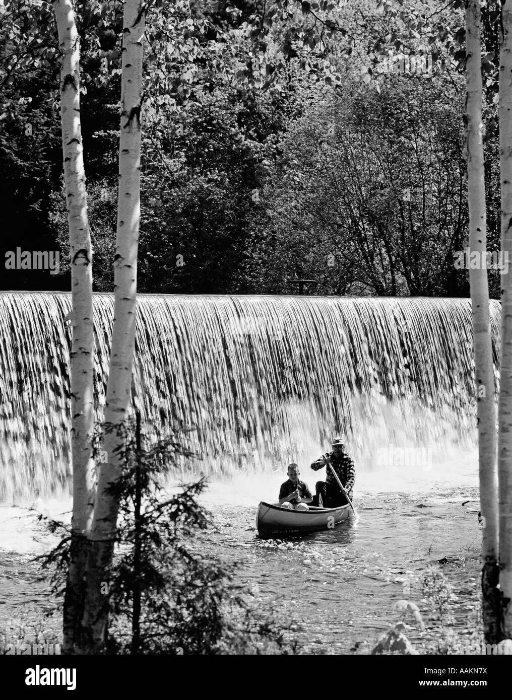 1970s FATHER & SON IN CANOE IN FRONT OF WATERFALL WITH FATHER ROWING ...