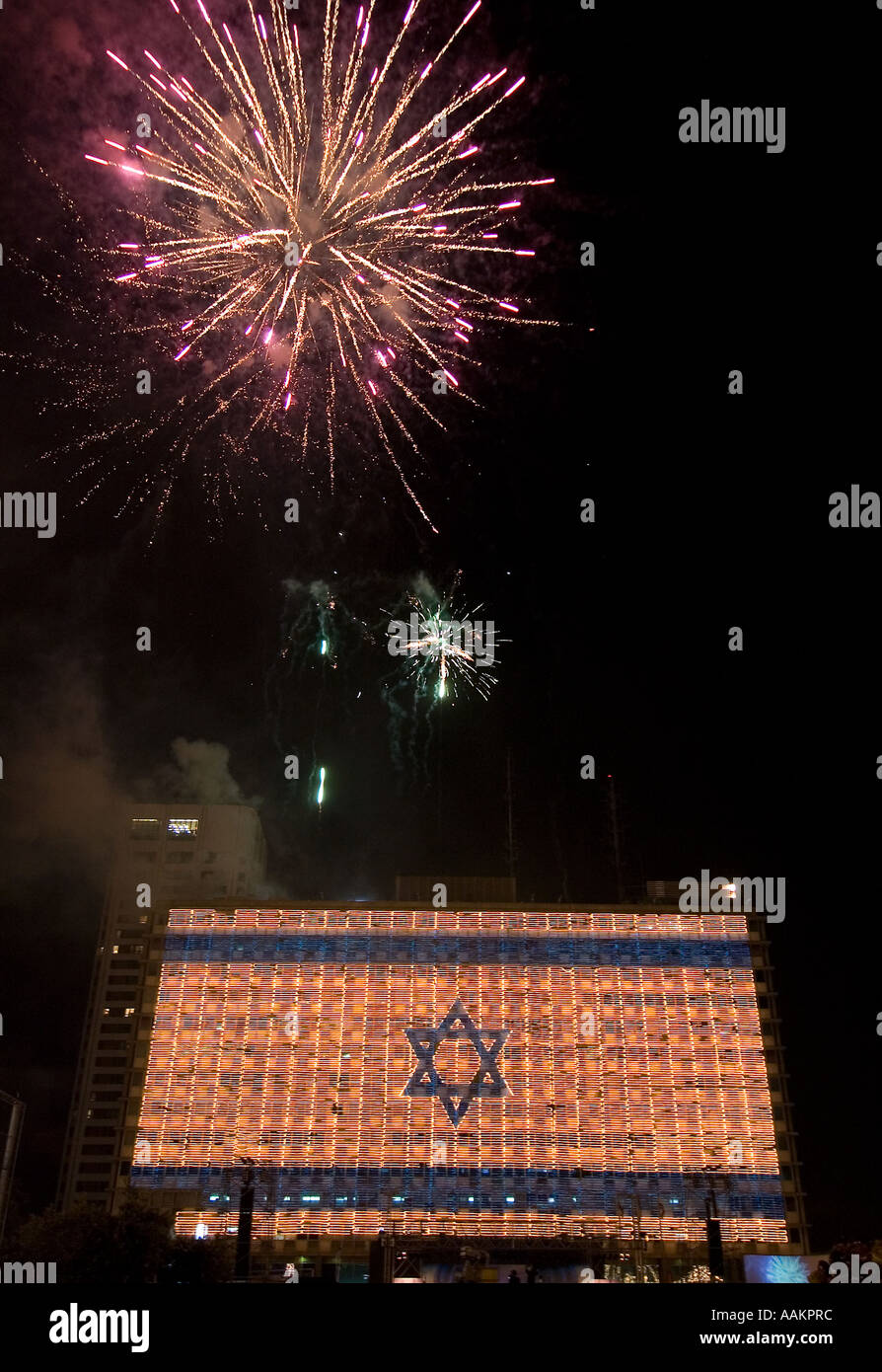 Fireworks light the sky over the illuminated city hall building bearing ...