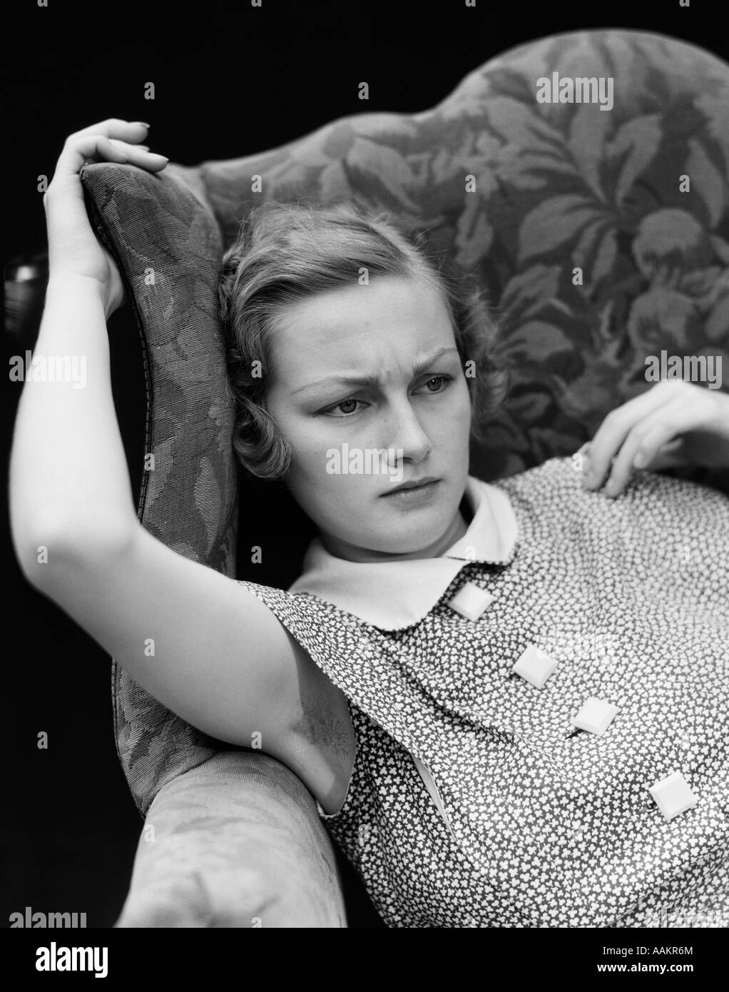 1930s WOMAN SITTING SLUMPED POSITION WITH A WORRIED EXPRESSION AND A ...