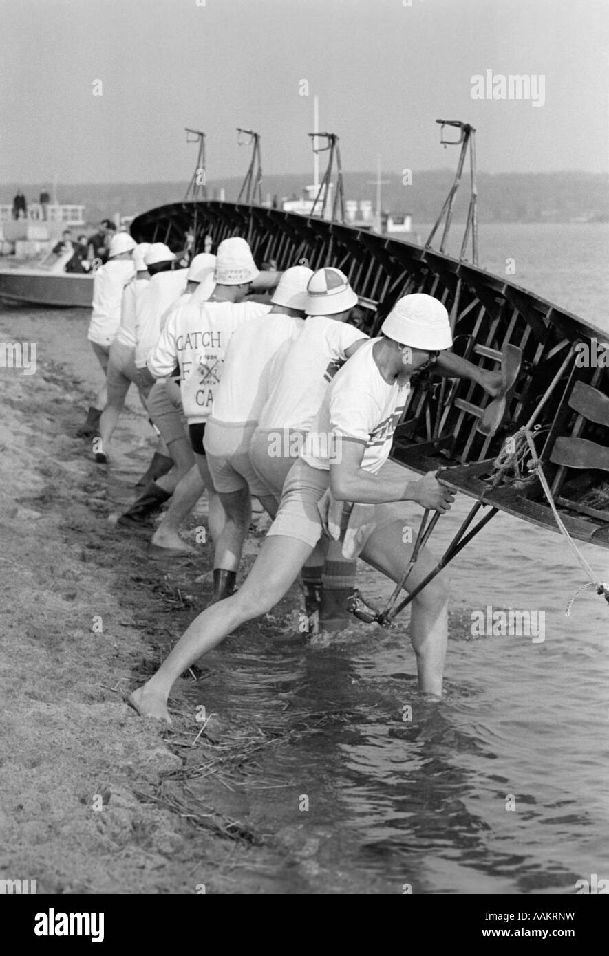 SCULLING TEAM LIFTING BOAT INTO THE WATER Stock Photo - Alamy
