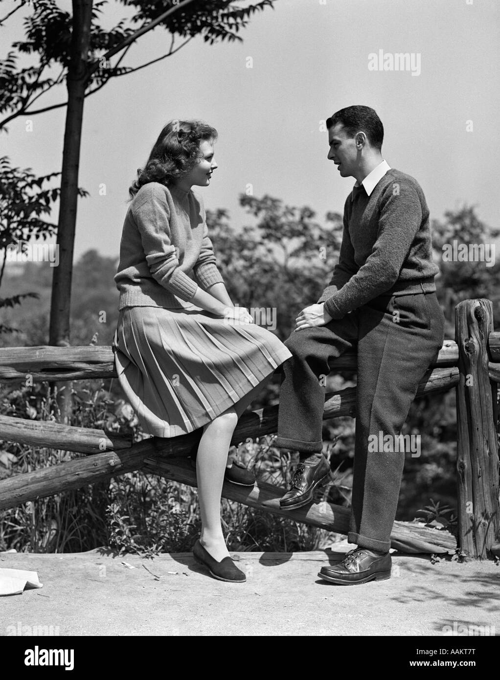 1940s YOUNG TEENAGE COUPLE SITTING TALKING ON RUSTIC WOODEN FENCE Stock ...