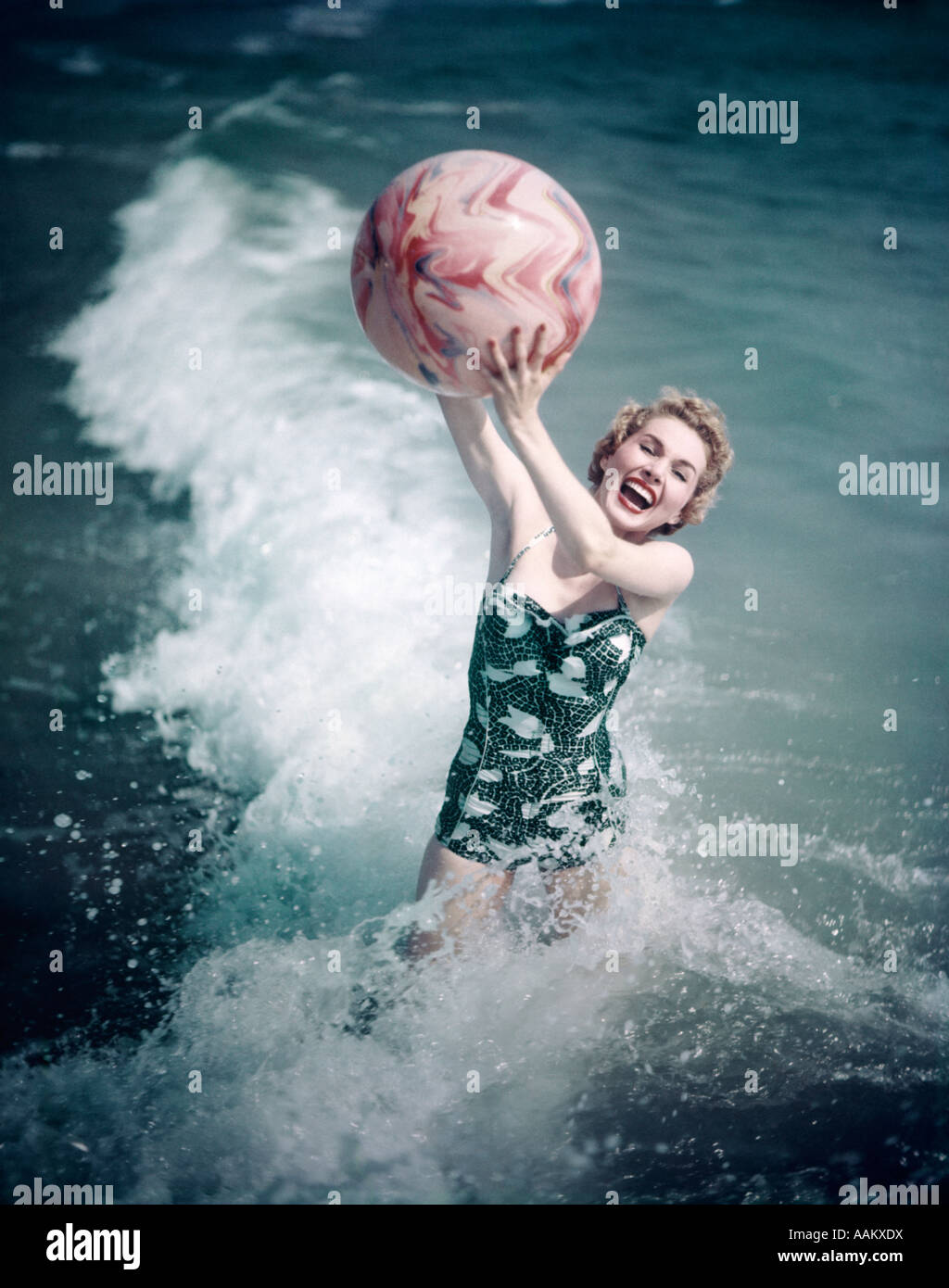 1950s WOMAN JUMPING IN SURF HOLDING UP BEACH BALL Stock Photo - Alamy