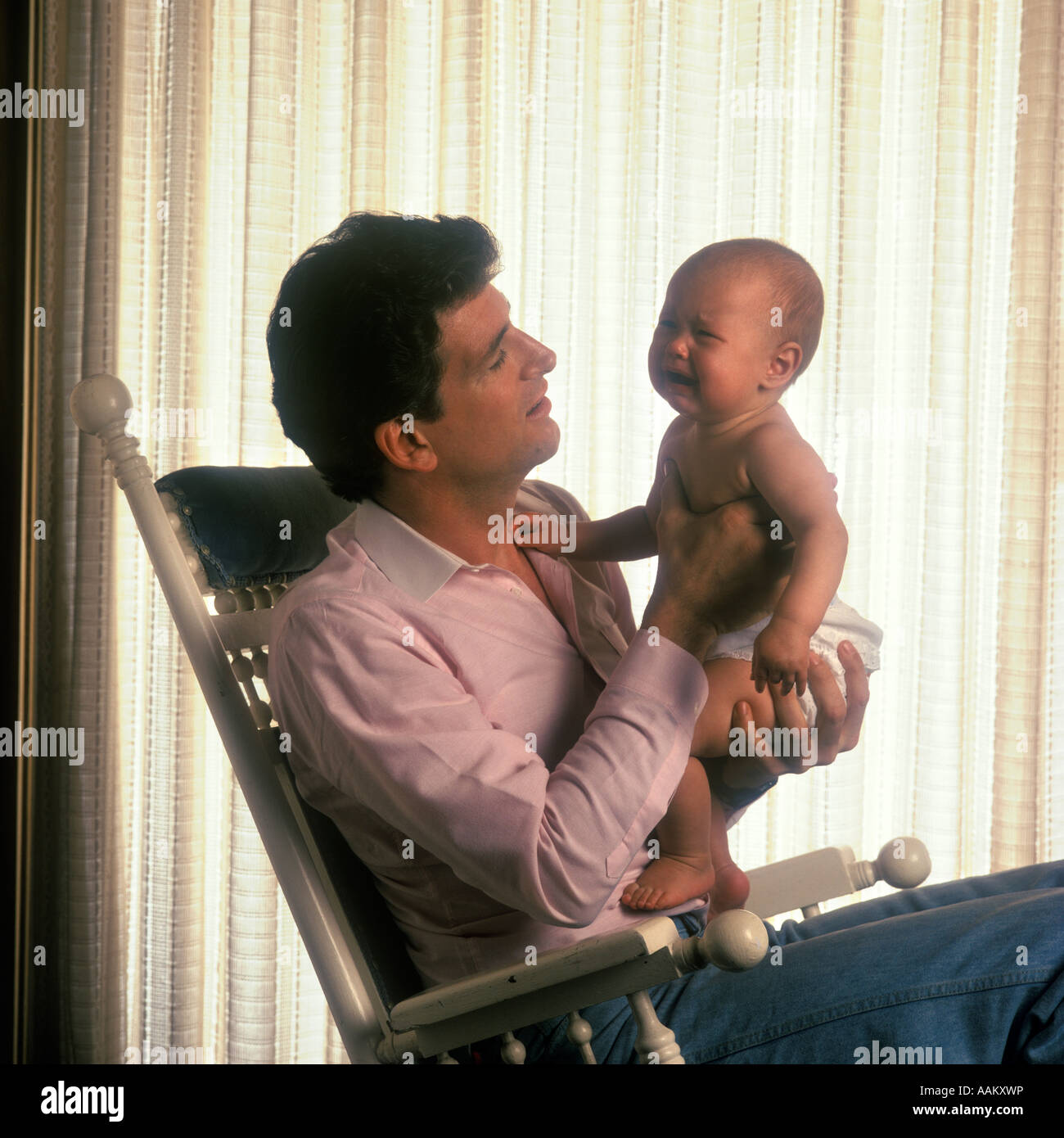 1980s FATHER SITTING IN ROCKING CHAIR HOLDING CRYING BABY FATHERHOOD ...