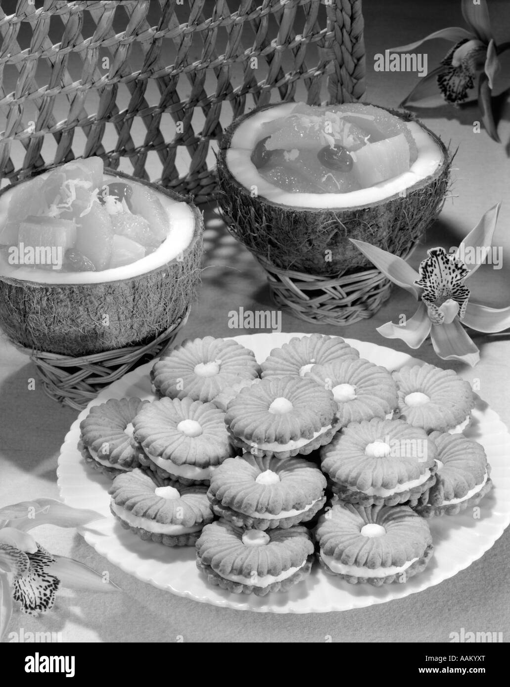 1950s STILL LIFE OF FILLED COOKIES ON A PLATE AND COCONUTS WITH FRUIT ...