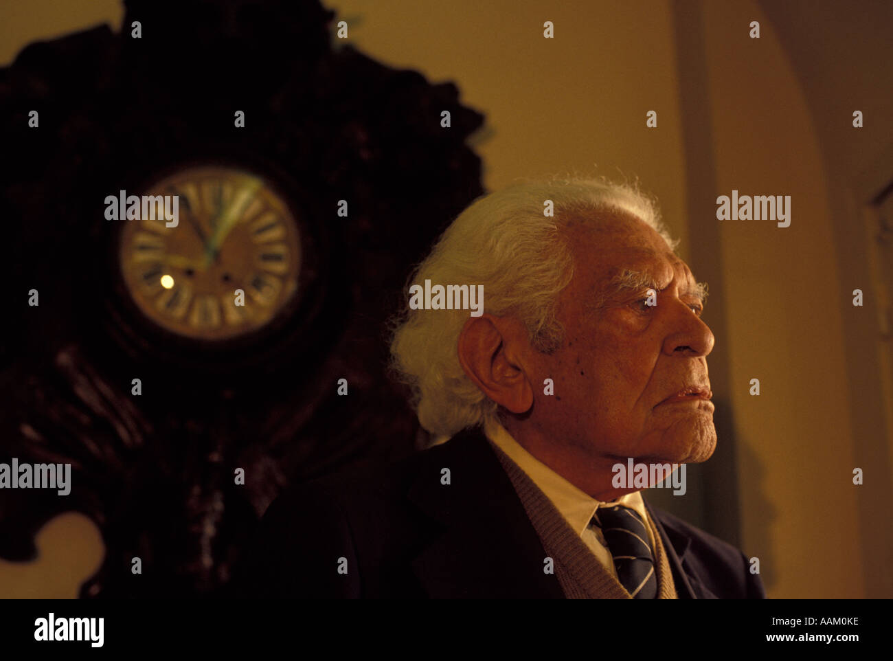Old man wearing suit and tie in front of a wall clock, timepiece Stock ...