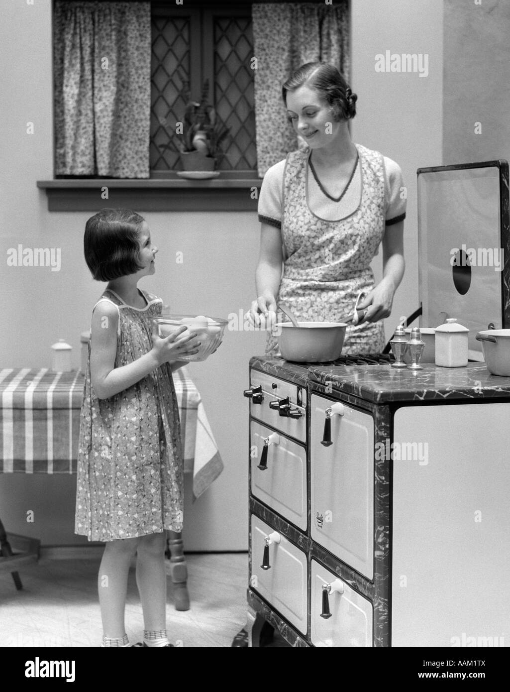 1920s YOUNG GIRL HELPING MOTHER COOK IN HOME KITCHEN INDOOR Stock Photo ...