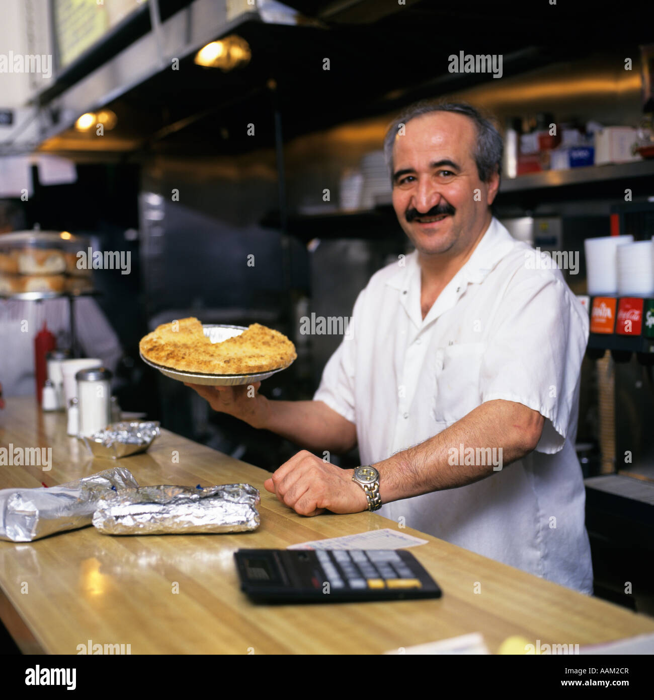 PORTRAIT SMILING MAN WORKING BEHIND COUNTER IN DINER HOLDING PIE Stock ...