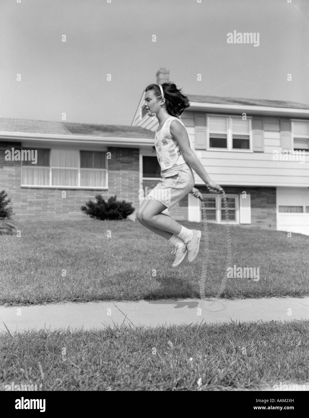 1960s GIRL JUMPING ROPE ON SIDEWALK JUMP IN FRONT OF HOUSE WEAR SUMMER ...