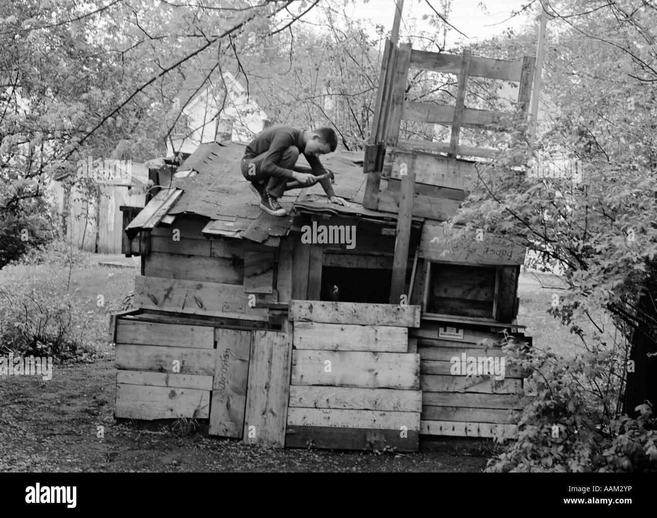 1960s BOY ON ROOF OF SHACK HOUSE FORT CASTLE NAILING DOWN SHINGLE WITH ...