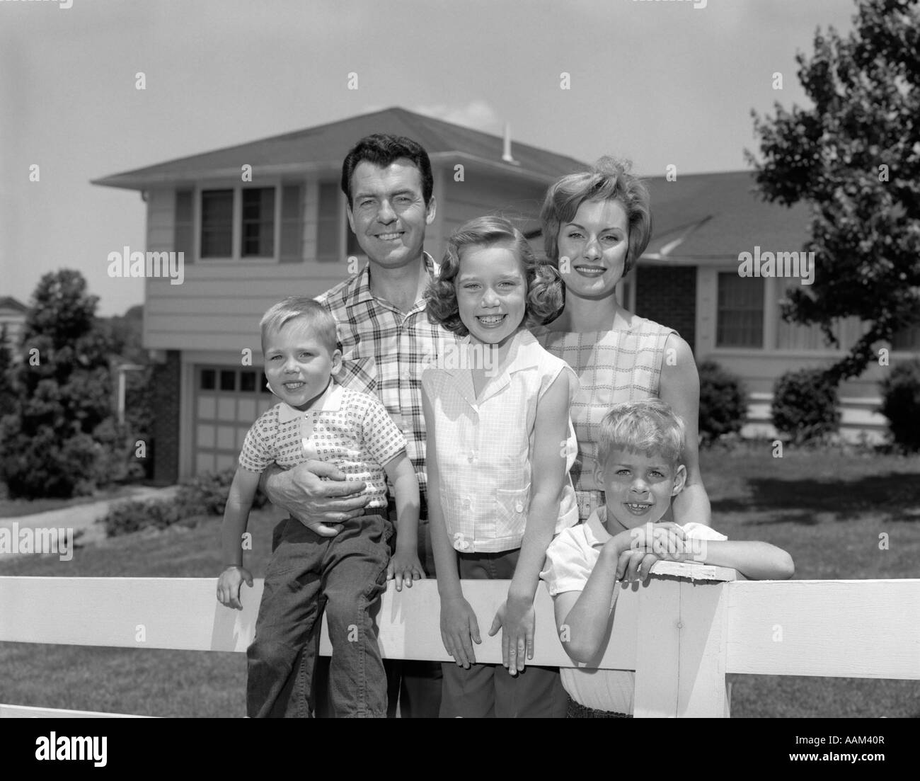 1960s FAMILY PORTRAIT IN FRONT OF HOUSE ON FENCE Stock Photo - Alamy