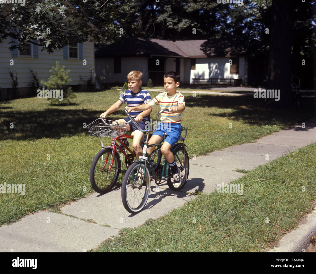1970s TWO BOYS RIDING BIKES DOWN SUBURBAN NEIGHBORHOOD SIDEWALK Stock ...