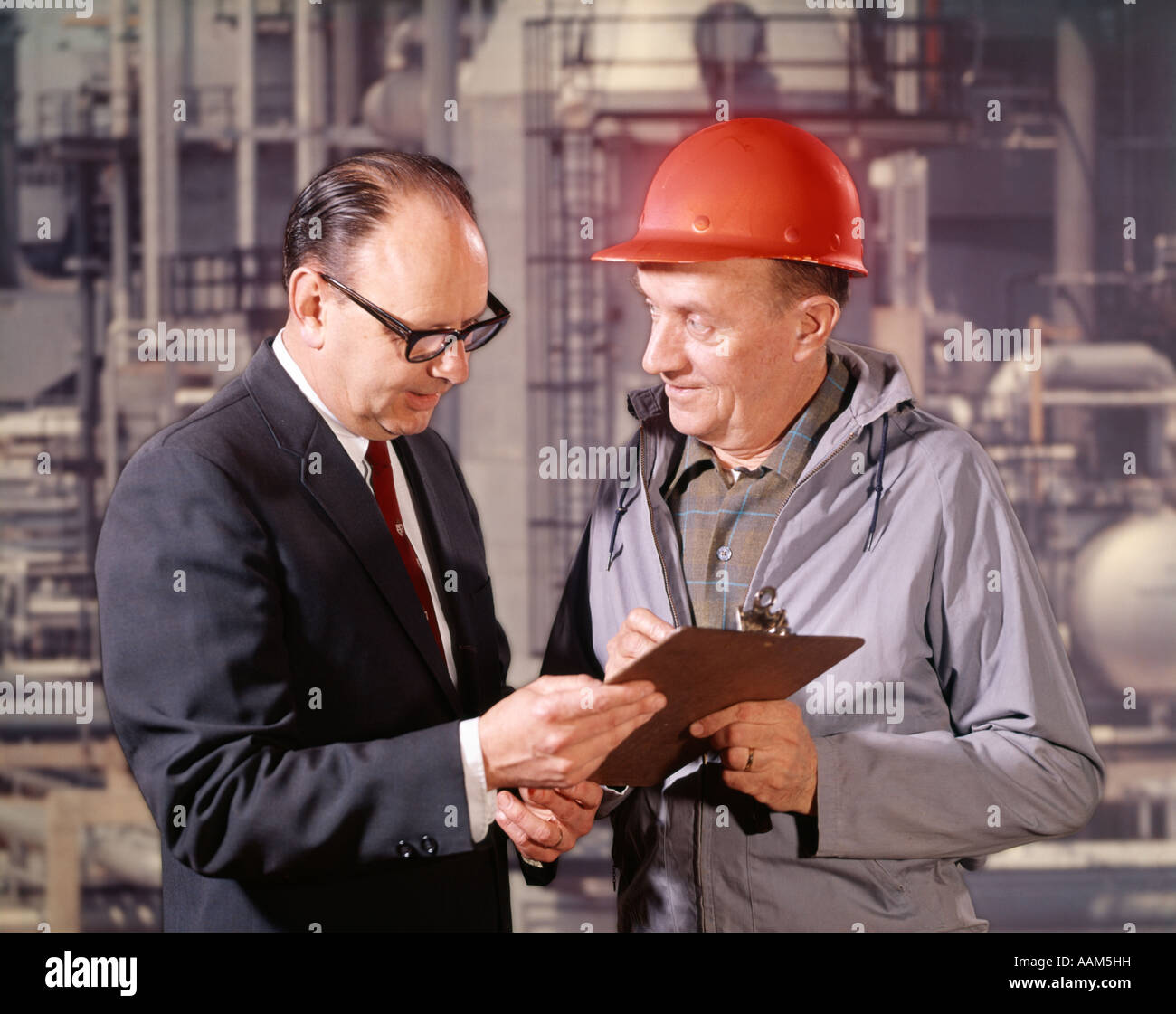 1960s EXECUTIVE AND ENGINEER WITH CLIPBOARD TALKING FACTORY REFINERY IN ...