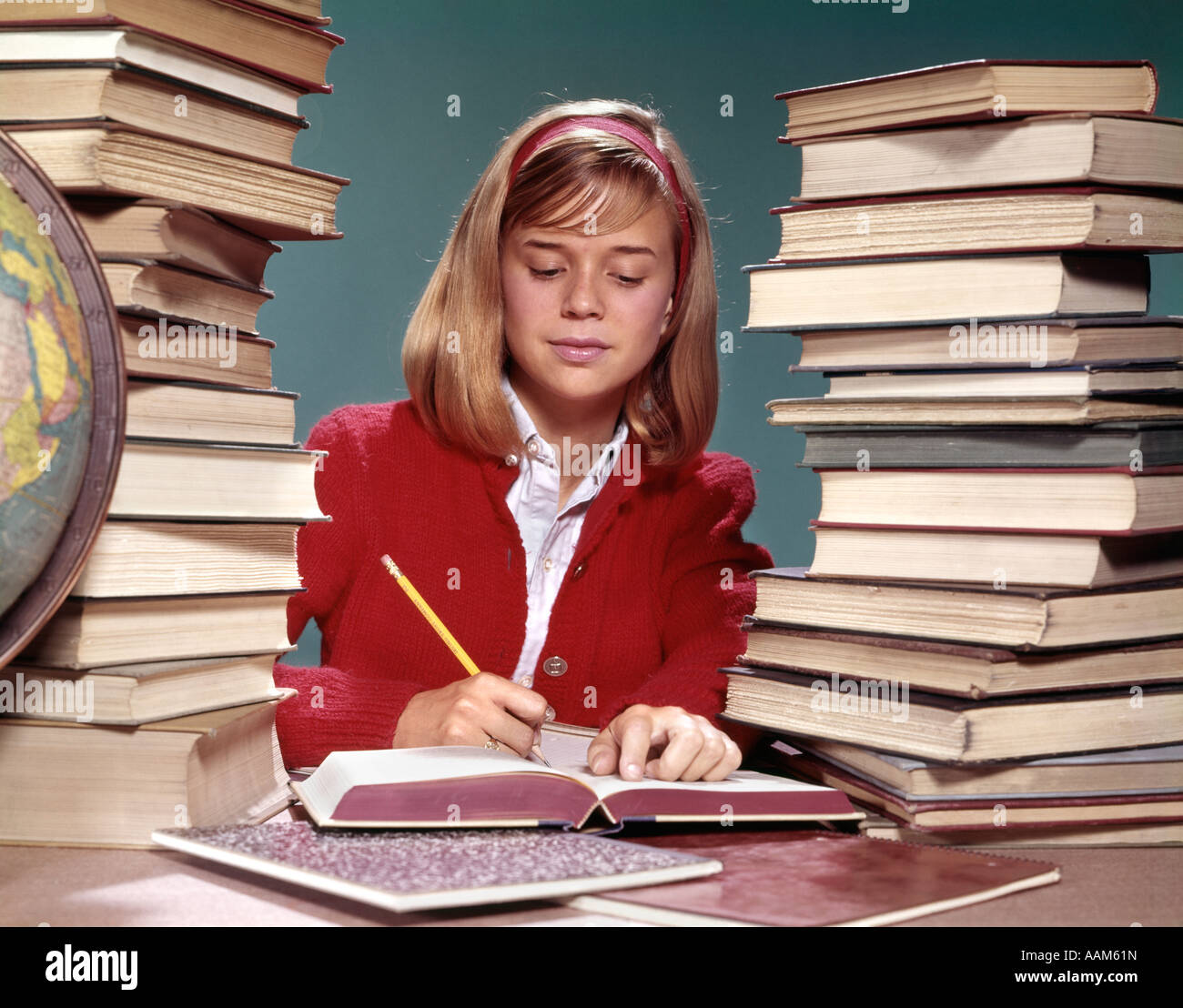 1960s TEENAGED GIRL WITH BOOKS STACKED ON BOTH SIDES OF HER AND GLOBE ...