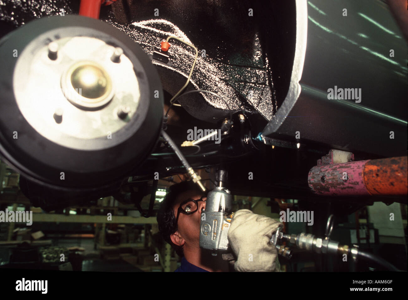 Mechanic working under a vehicle. Factory worker at automobile industry ...