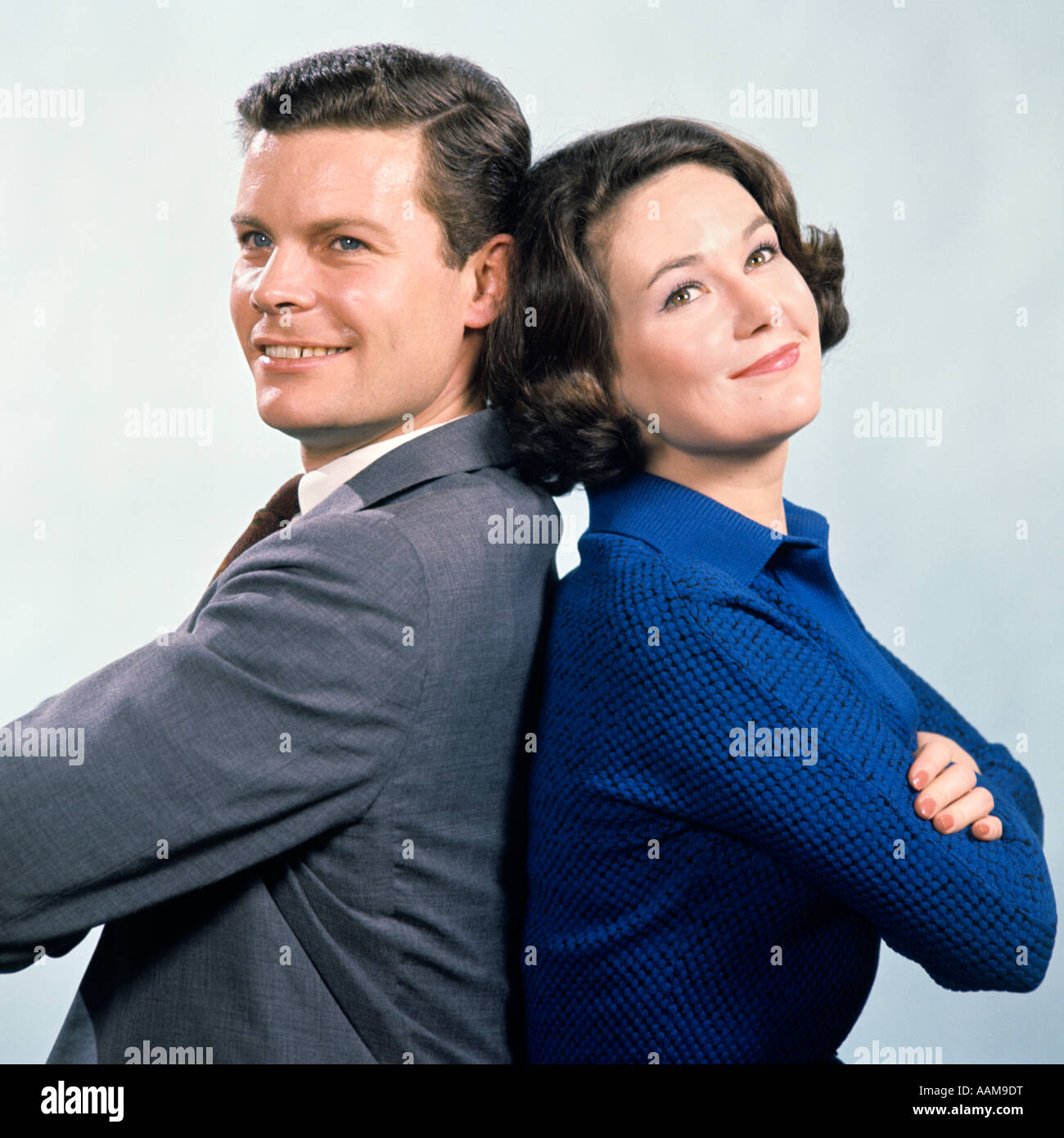 1960s SMILING MAN AND WOMAN STANDING BACK TO BACK WITH ARMS FOLDED ...