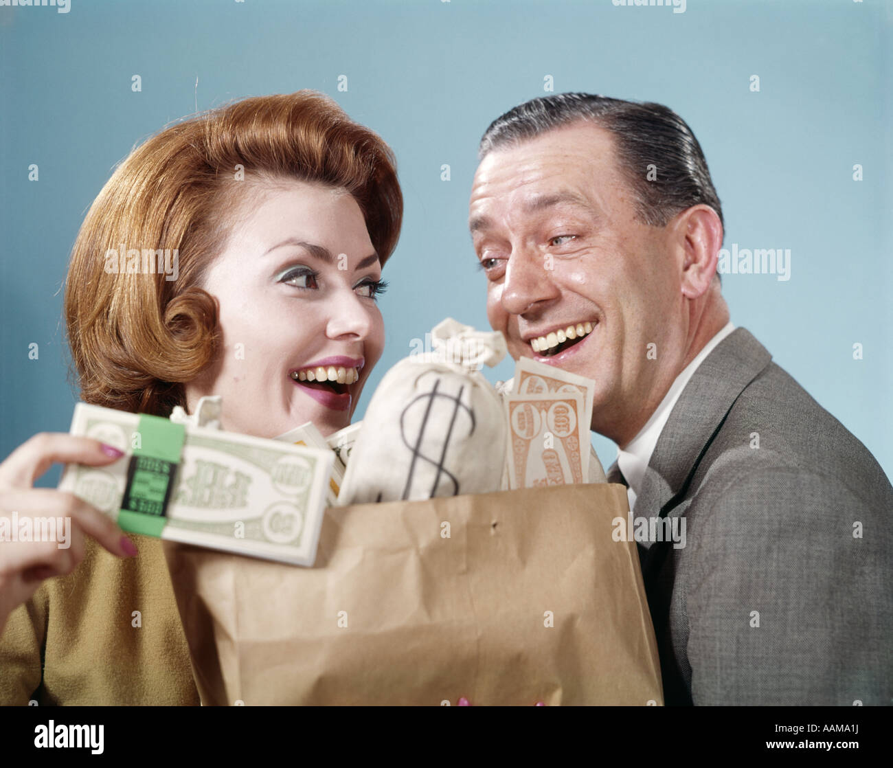 1960s COUPLE MAN WOMAN HOLDING SHOPPING BAG FULL OF MONEY CURRENCY ...