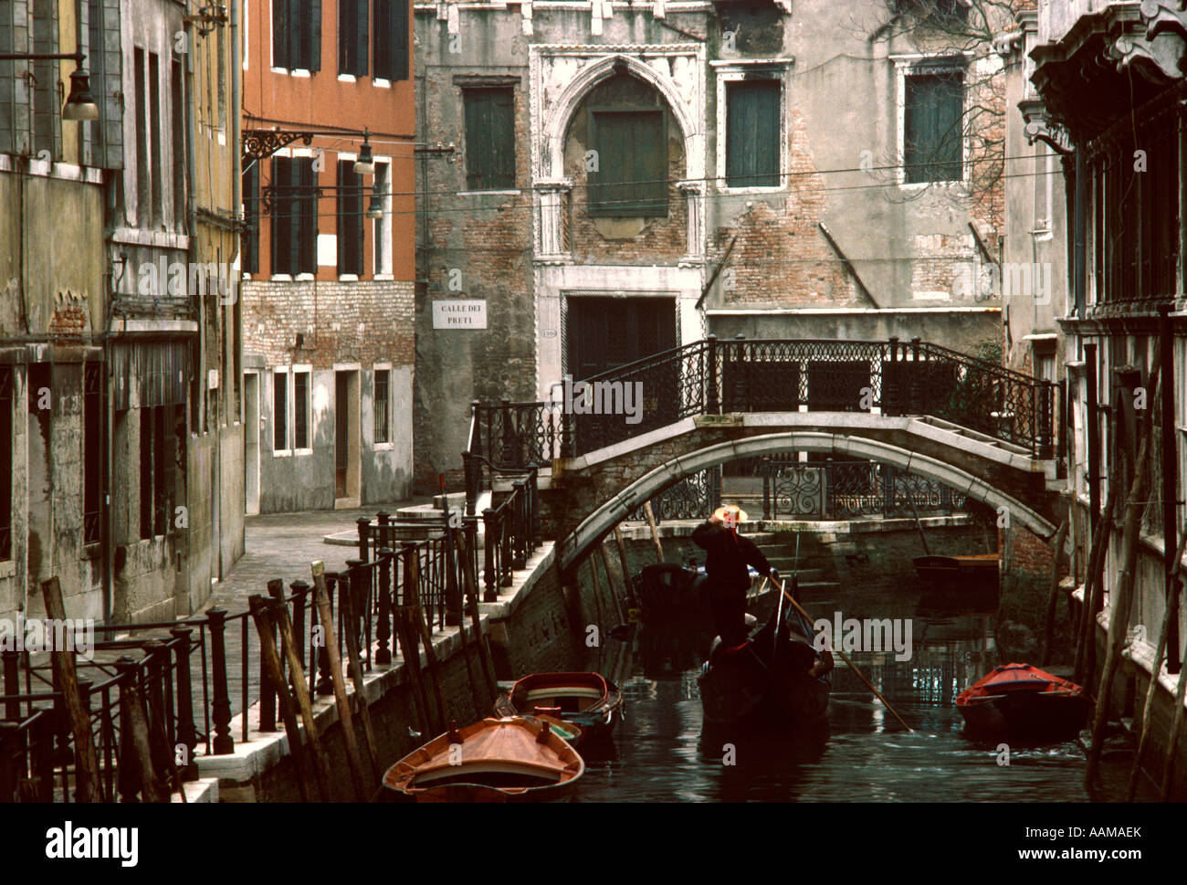 CANAL BETWEEN BUILDINGS GONDOLIER ROWING GONDOLA UNDER BRIDGE VENICE ...