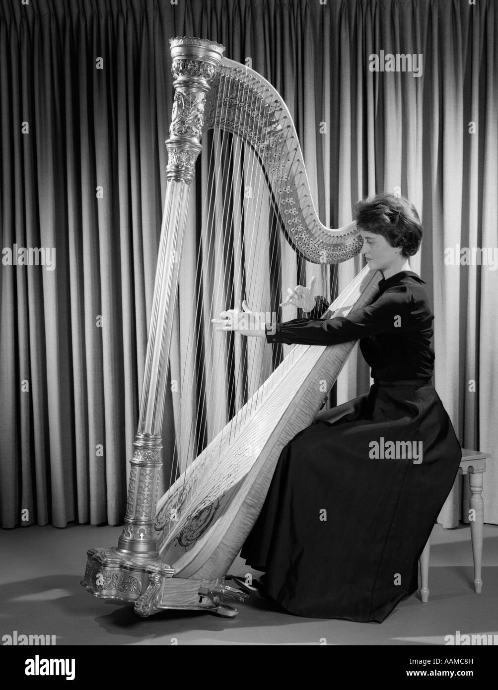 1960s WOMAN MUSICIAN IN FORMAL DRESS PERFORMING PLAYING HARP ON STAGE ...