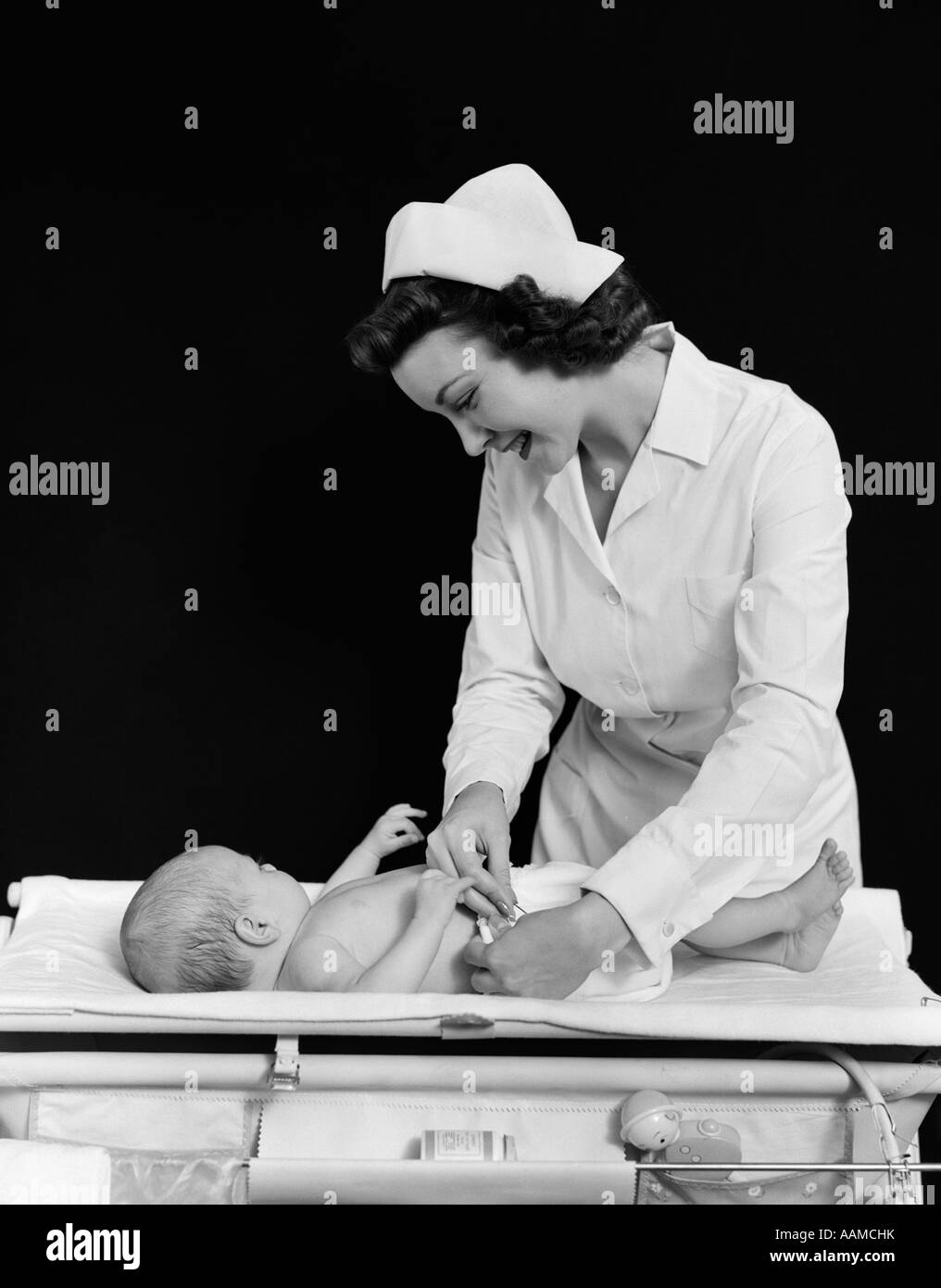 1940s SMILING WOMAN NURSE CHANGING BABY DIAPER IN NURSERY Stock Photo ...