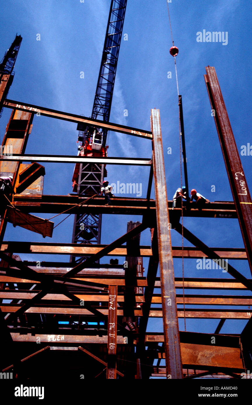 Construction workers high above ground on steel beams with a large ...