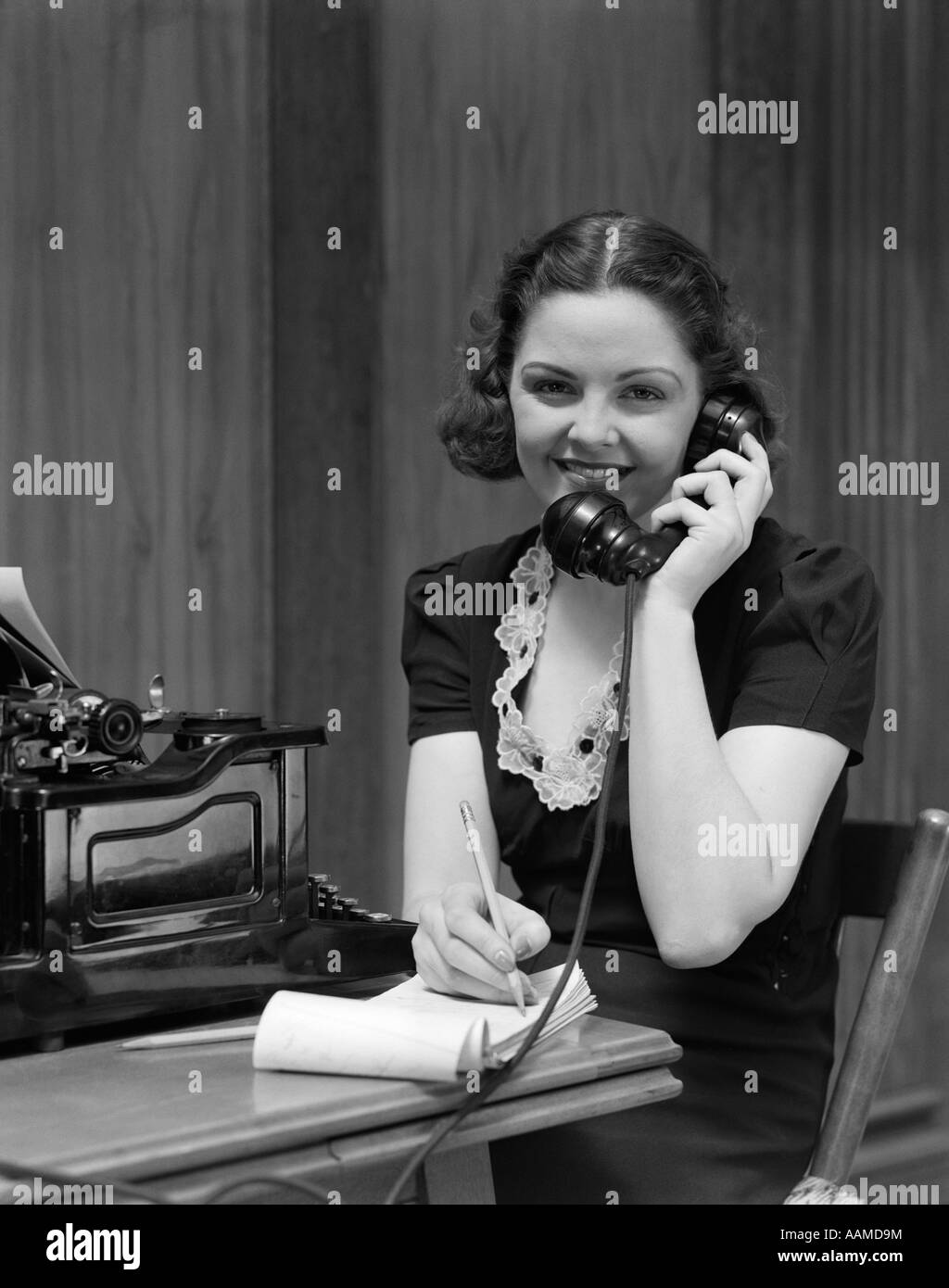 1930s SMILING YOUNG WOMAN RECEPTIONIST SECRETARY SITTING AT DESK IN ...