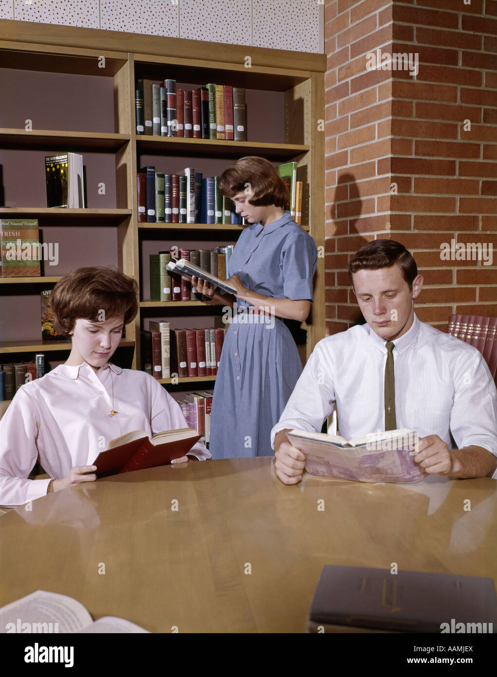 1960 1960s 3 STUDENTS BOY 2 GIRLS IN LIBRARY READING STUDY STUDYING ...