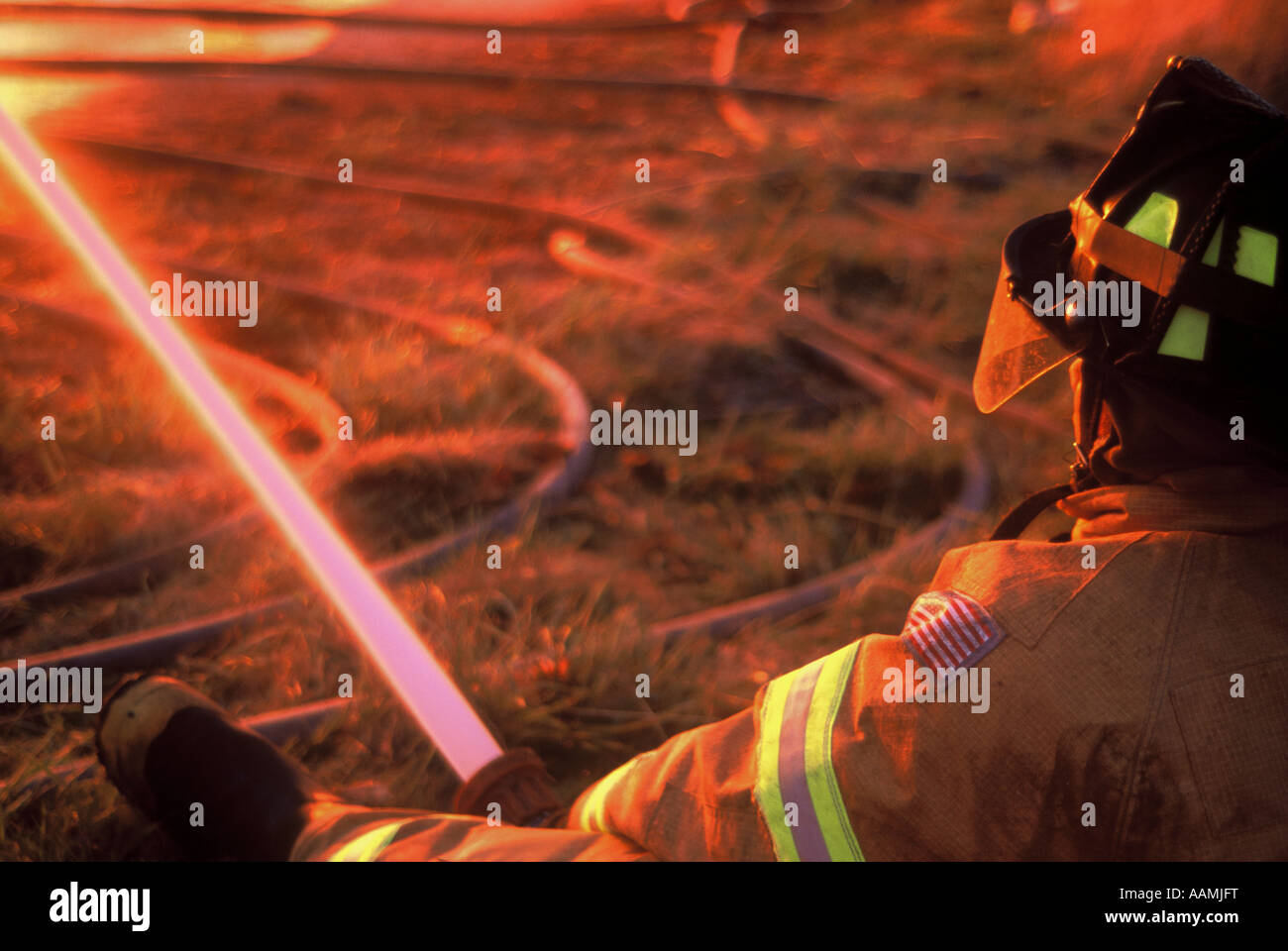 Fire fighter sitting with a hose putting water on a fire Stock Photo ...