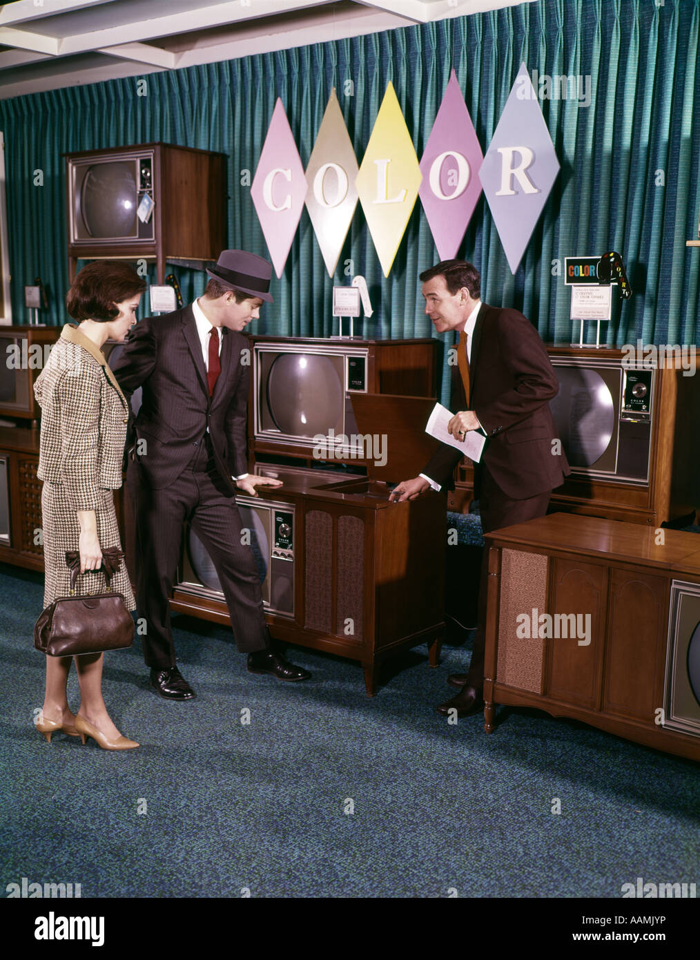 1960s COUPLE WITH SALESMAN LOOKING AT COLOR TELEVISIONS IN DEPARTMENT ...