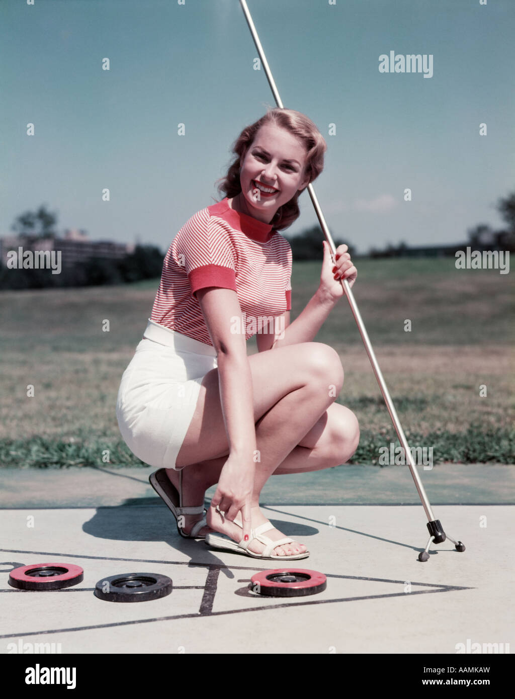 1950s SMILING BLONDE WOMAN KNEELING ON SHUFFLEBOARD HOLDING CUE POINT ...