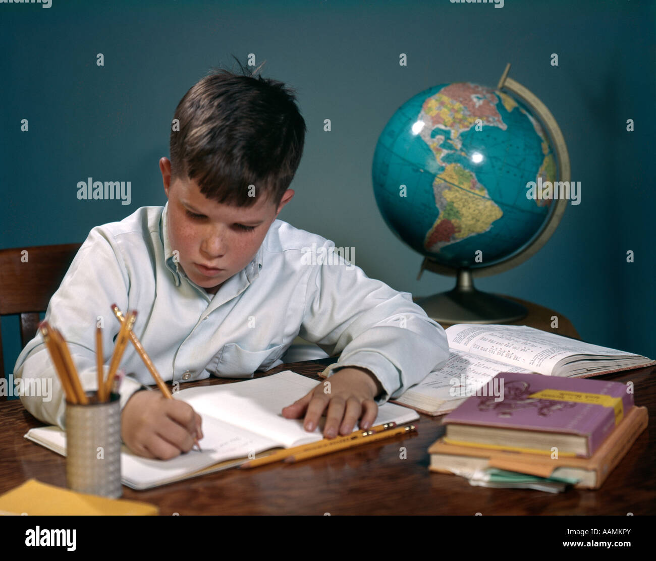 1960s 1970s BOY DOING HOMEWORK AT DESK WRITING NOTEBOOK BOOKS GLOBE ...