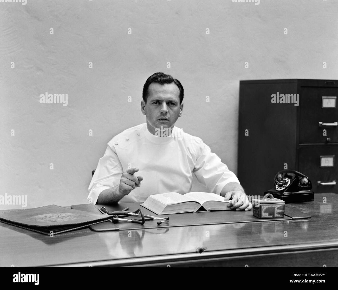 1940s DOCTOR OFFICE DESK POINTING BOOK READING Stock Photo - Alamy