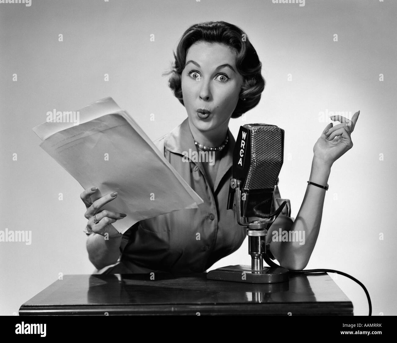 1950s WOMAN TALKING INTO RADIO MICROPHONE HOLDING PAPERS EXAGGERATED ...