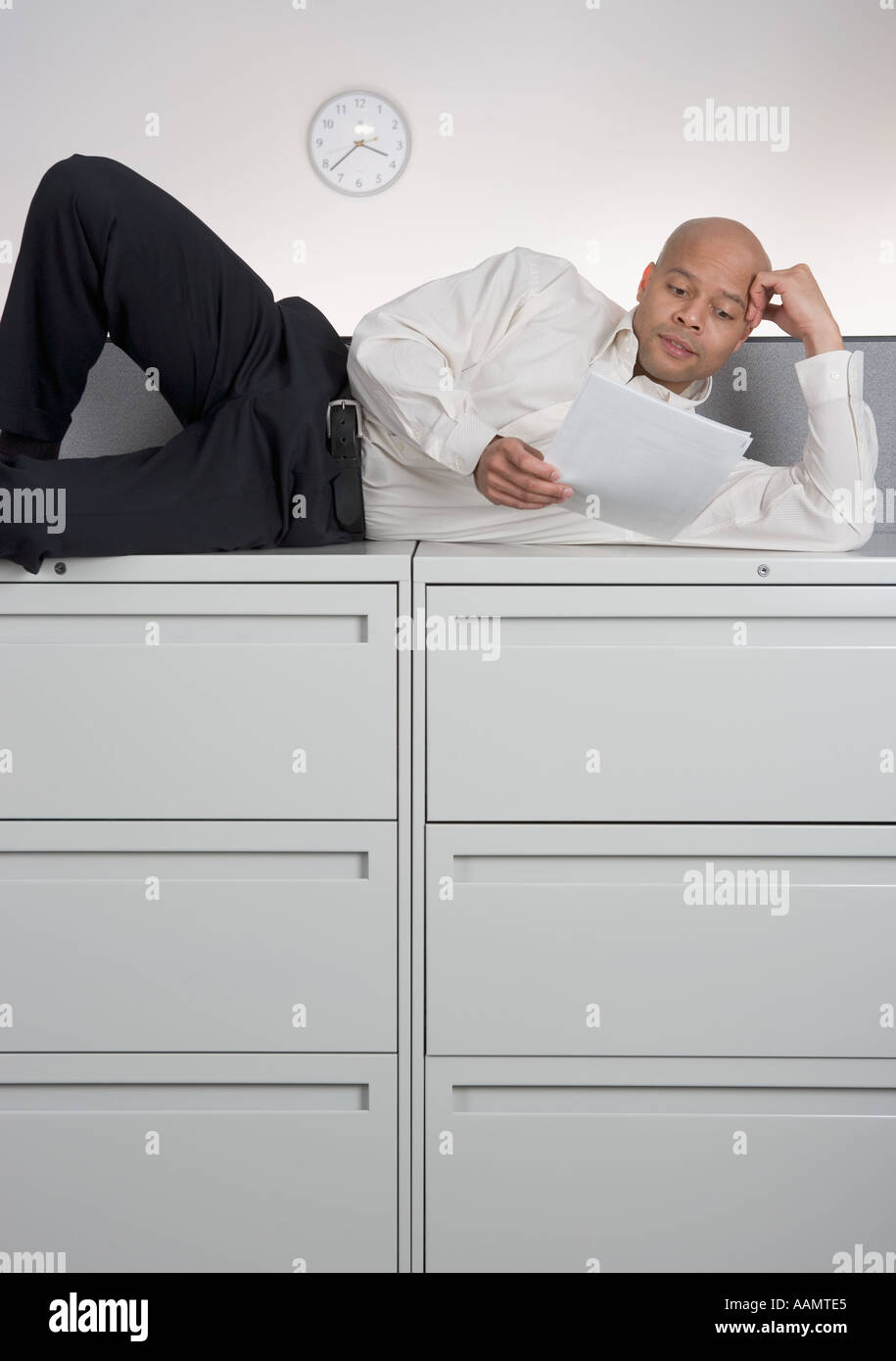 Businessman laying on filing cabinet Stock Photo - Alamy