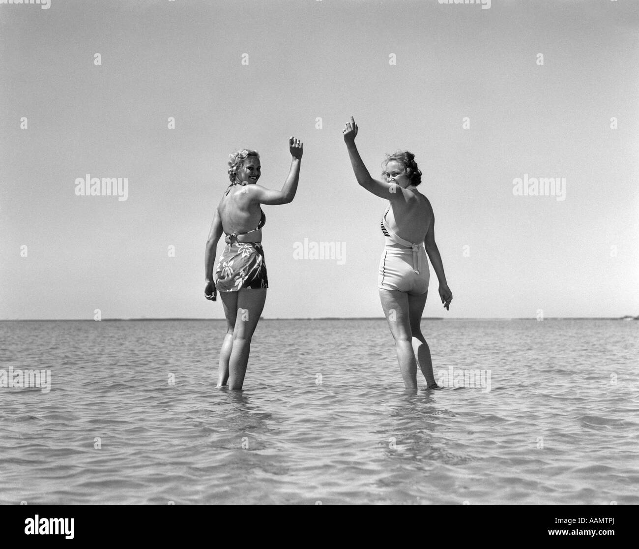1930s Two Girls Standing In Water Wearing Bathing Suits Looking Back
