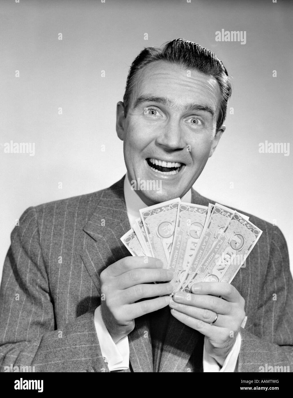 1950s HAPPY MAN WITH EXAGGERATED SMILE HOLDING FAN OF MONEY LOOKING AT ...