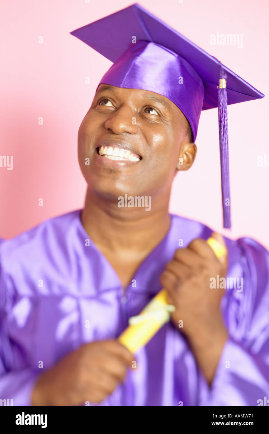 Man in cap and gown holding diploma Stock Photo - Alamy