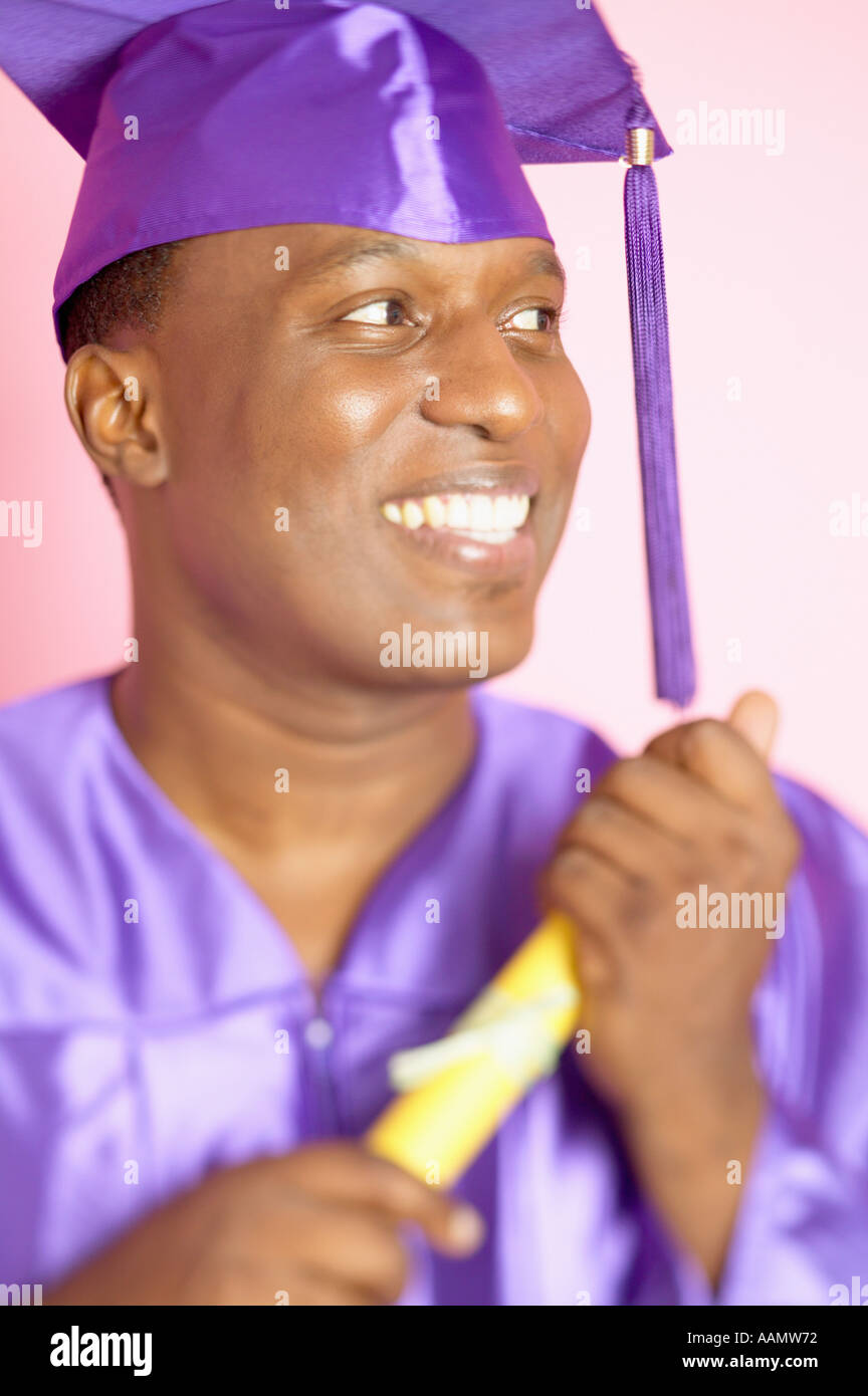 Man in cap and gown holding diploma Stock Photo - Alamy